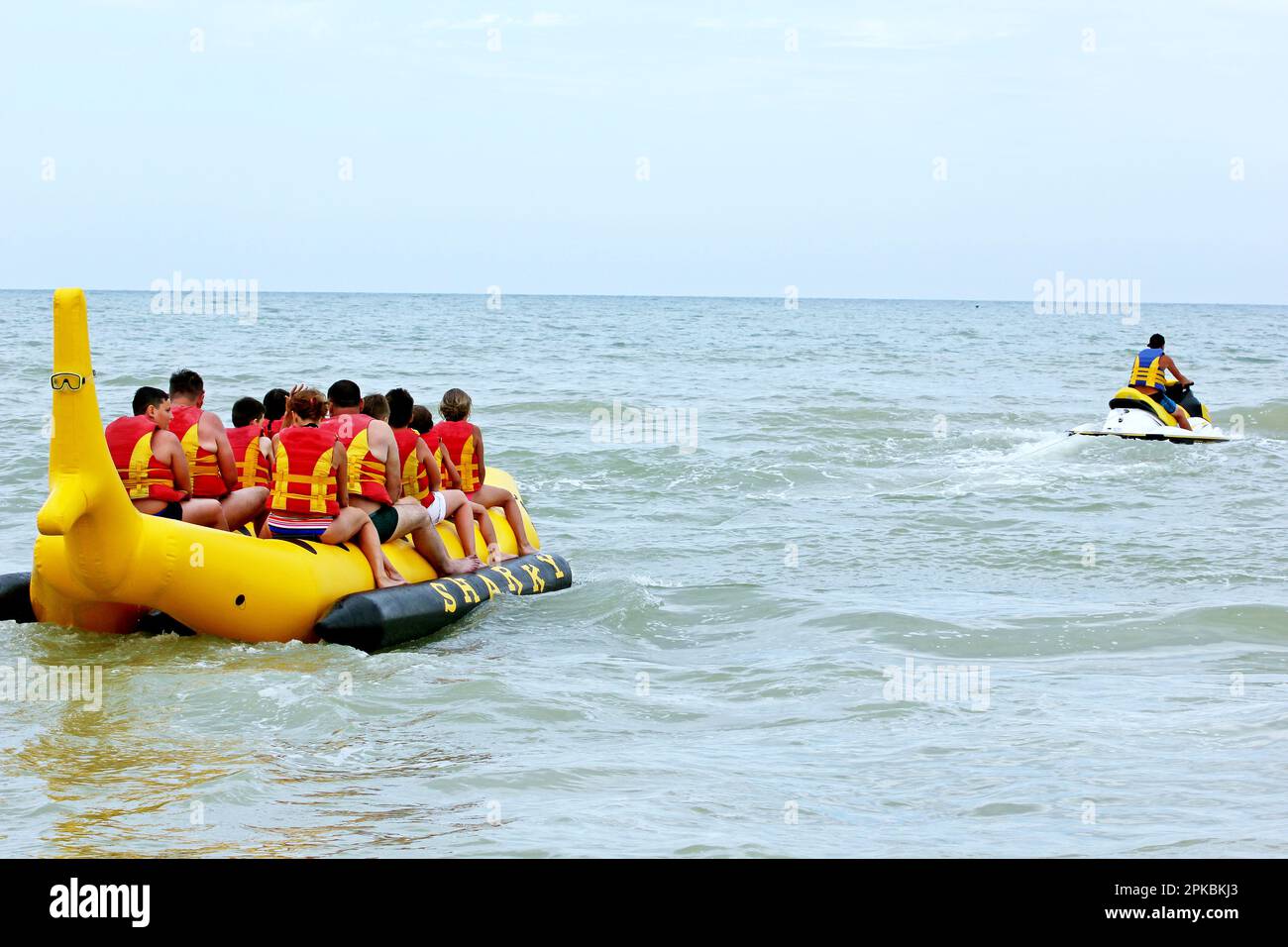 group of people riding an inflatable shark driven by a water bike Stock ...