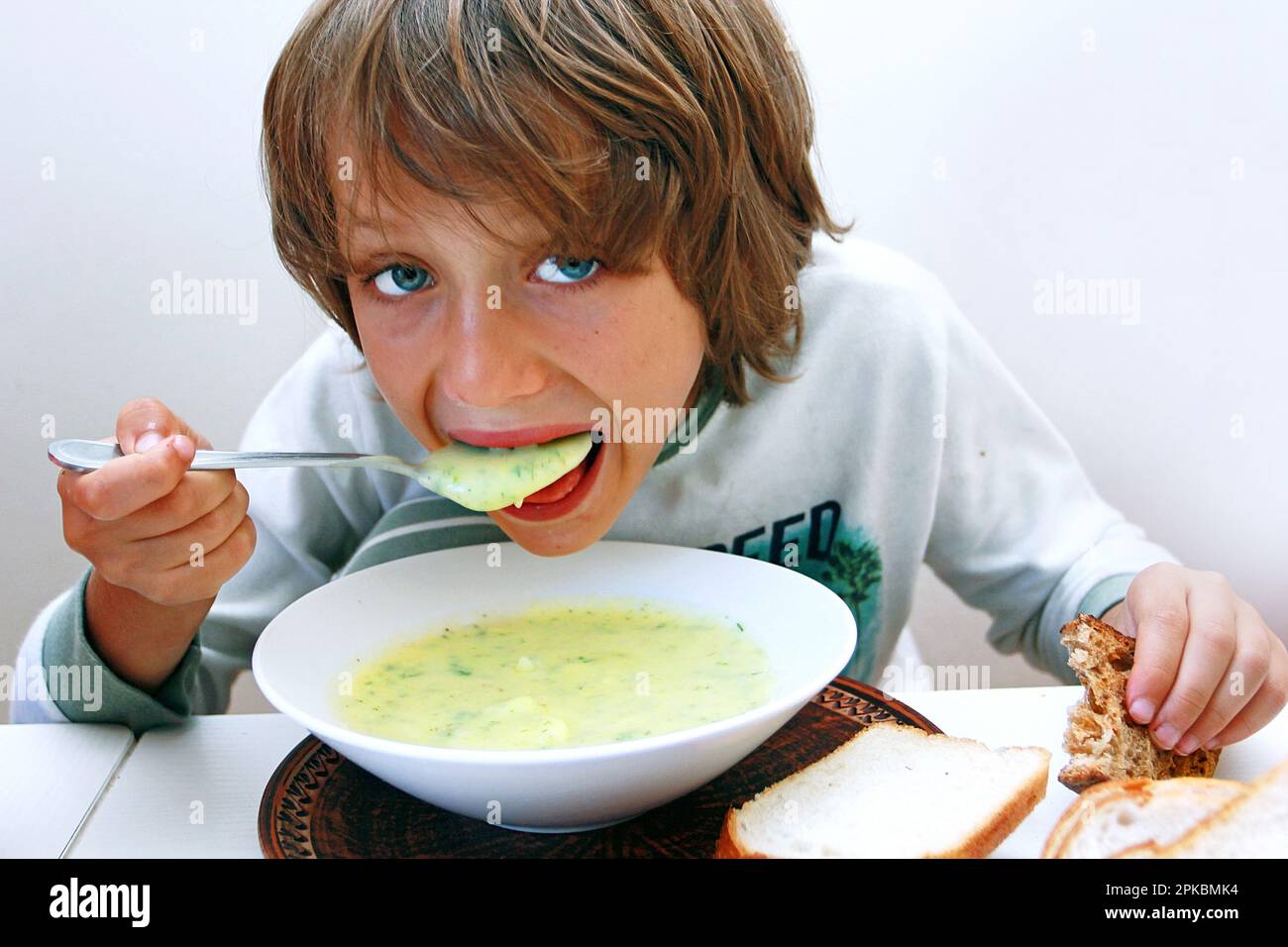 boy eating vegetable cream soup with bread at the dinner table lunch ...