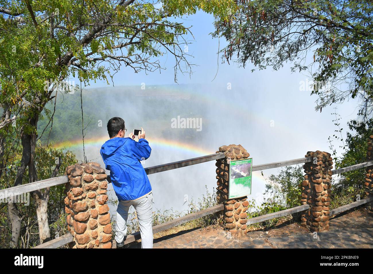 A tourist takes photos of the Victoria waterfall at the border between ...