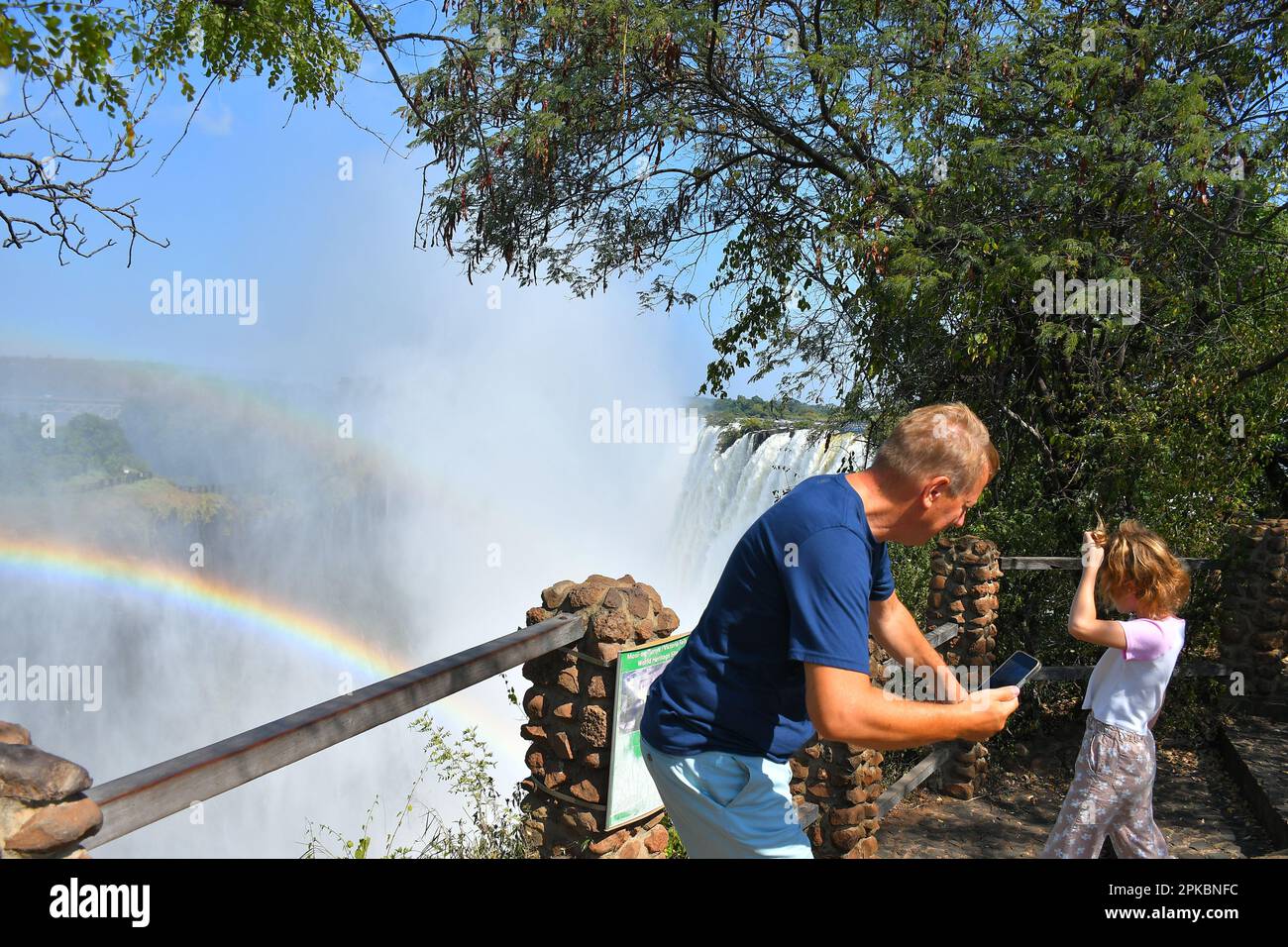 Tourists take photos of the Victoria waterfall at the border between ...