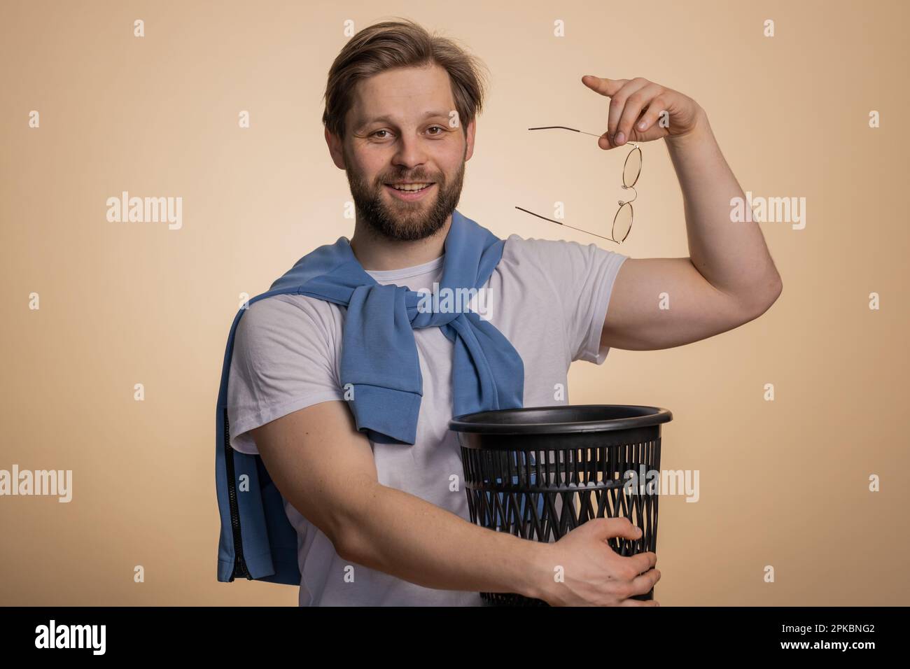 Caucasian bearded man taking off throwing out glasses into bin after ...