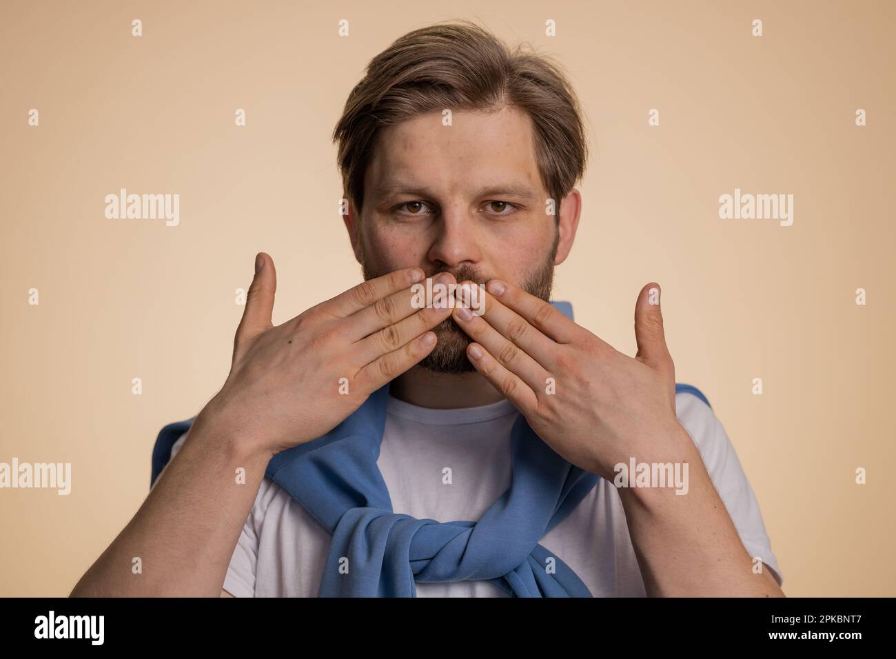 I will not say anyone. Frightened man closing his mouth with hand ...