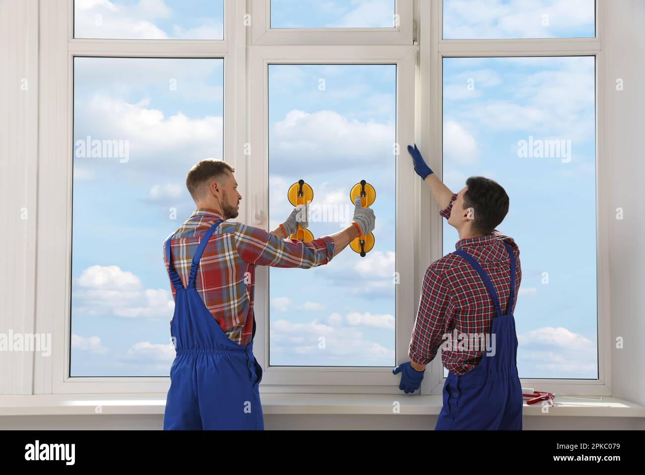 Workers using suction lifters during plastic window installation ...