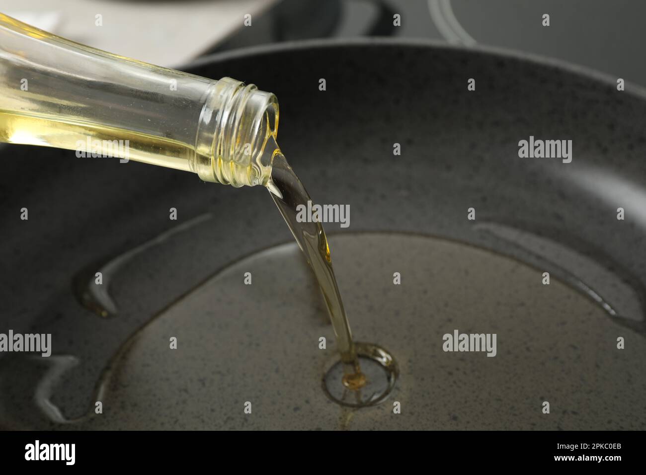 Pouring cooking oil from bottle into frying pan, closeup Stock Photo ...
