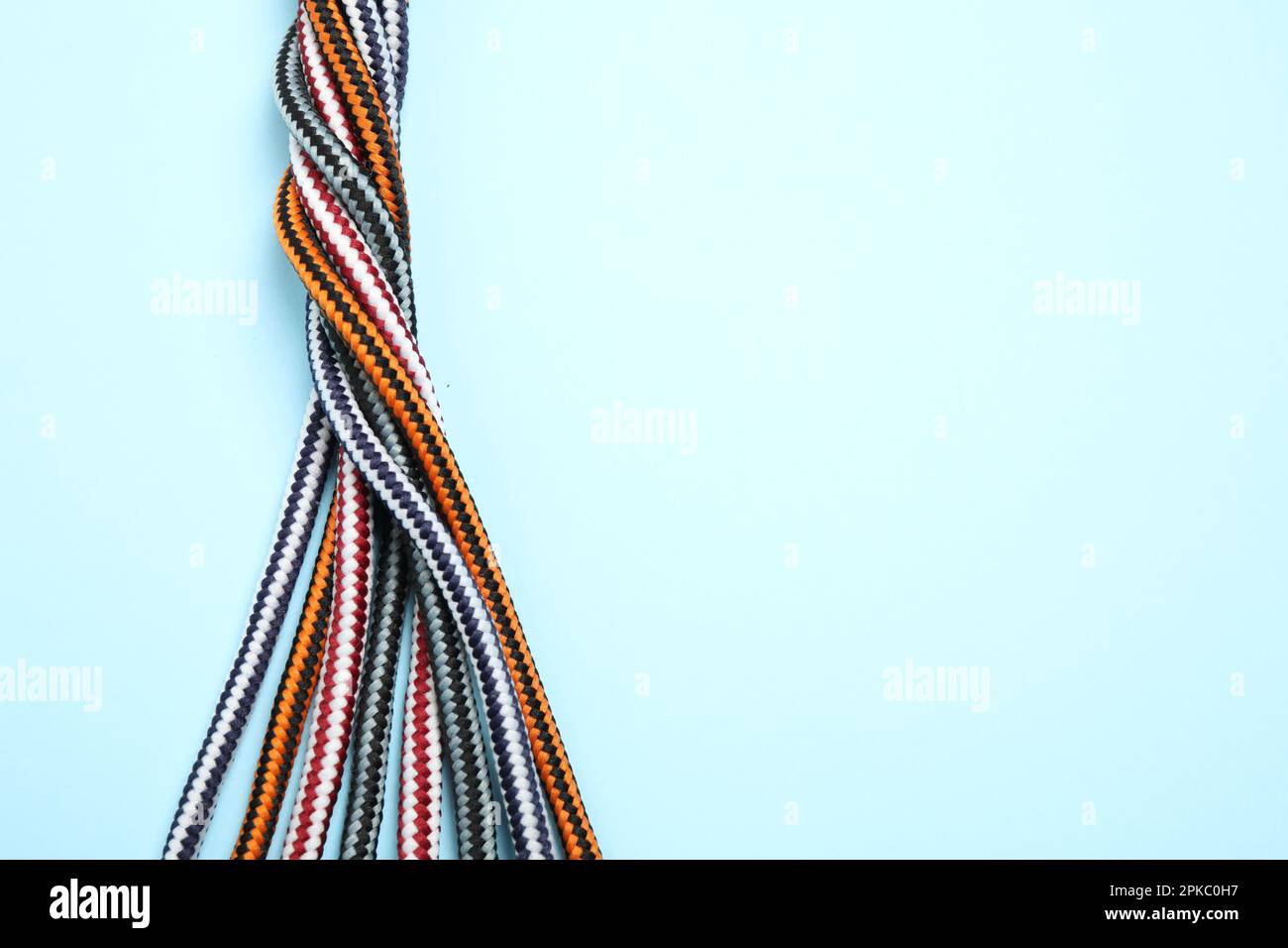 Top view of twisted colorful ropes on light blue background, space for ...