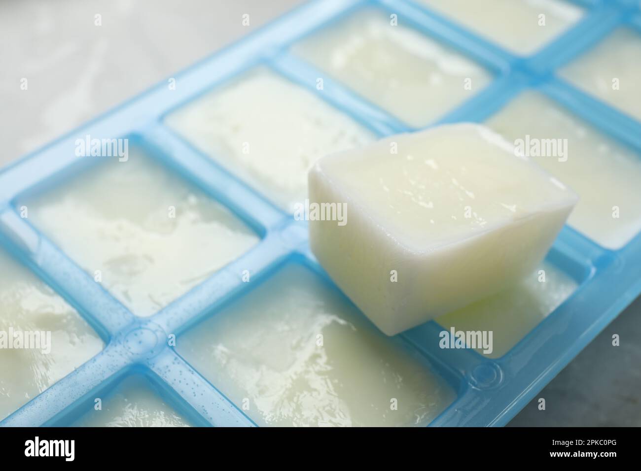 Ice cube tray with frozen milk on grey table, closeup Stock Photo - Alamy