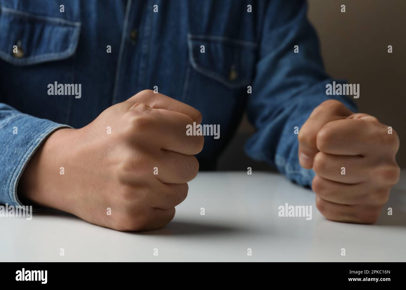 Man clenching fists at table while restraining anger, closeup Stock ...