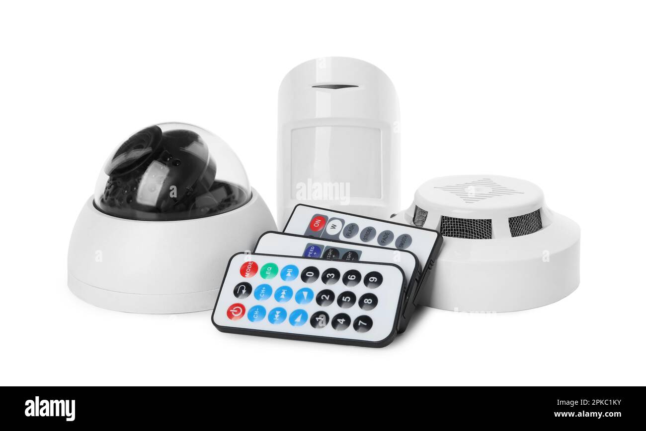 CCTV camera, remote controls, smoke and movement detectors on white ...