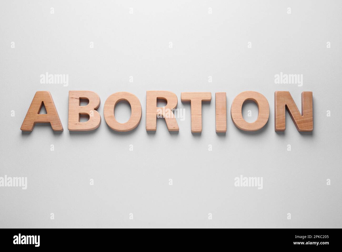 Word Abortion made of wooden letters on light grey background, flat lay ...