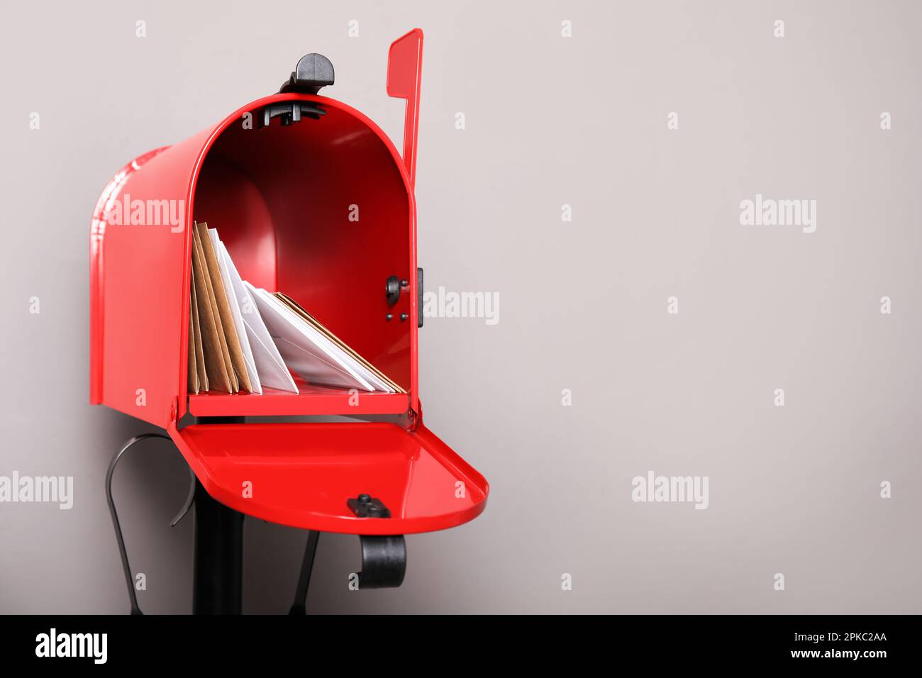 Open red letter box with envelopes against grey background. Space for ...