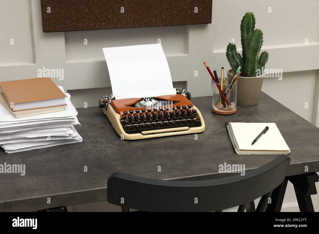 Typewriter and stack of papers on dark table in room. Writer's ...