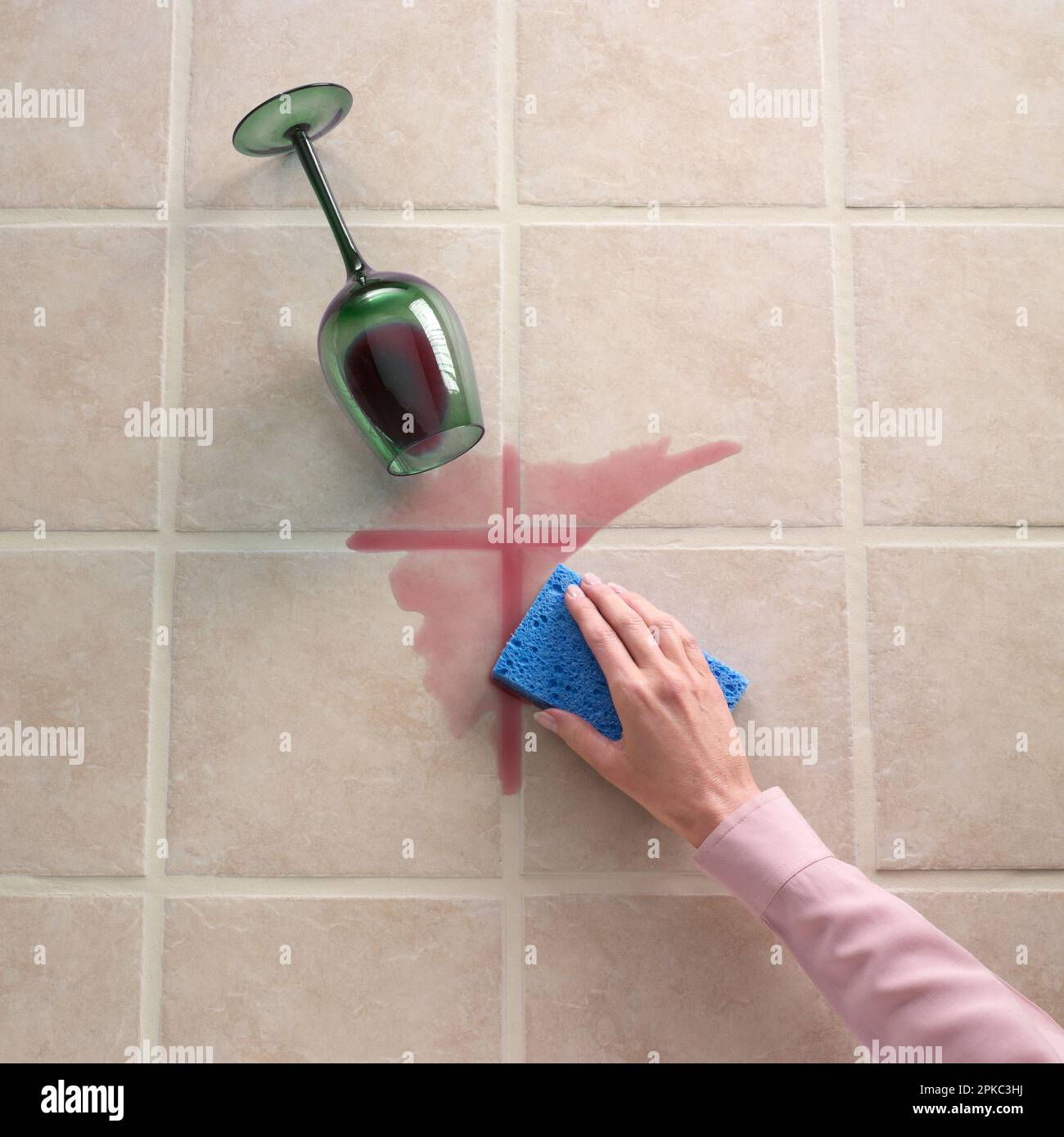 woman's hand holding blue sponge wipes up spilled juice wine on tile ...