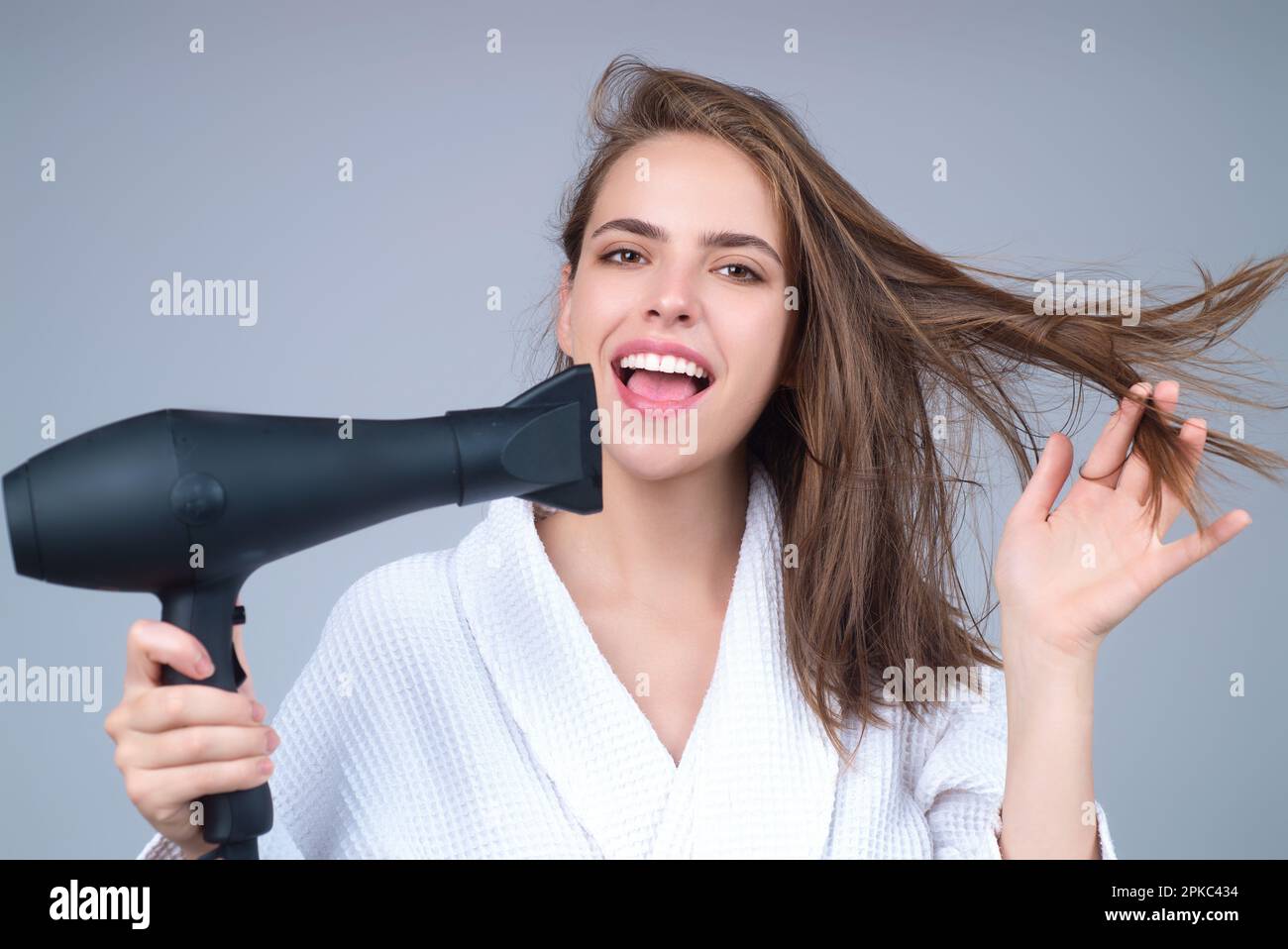 Beautiful woman drying her hair with a hairdryer isolated on studio ...