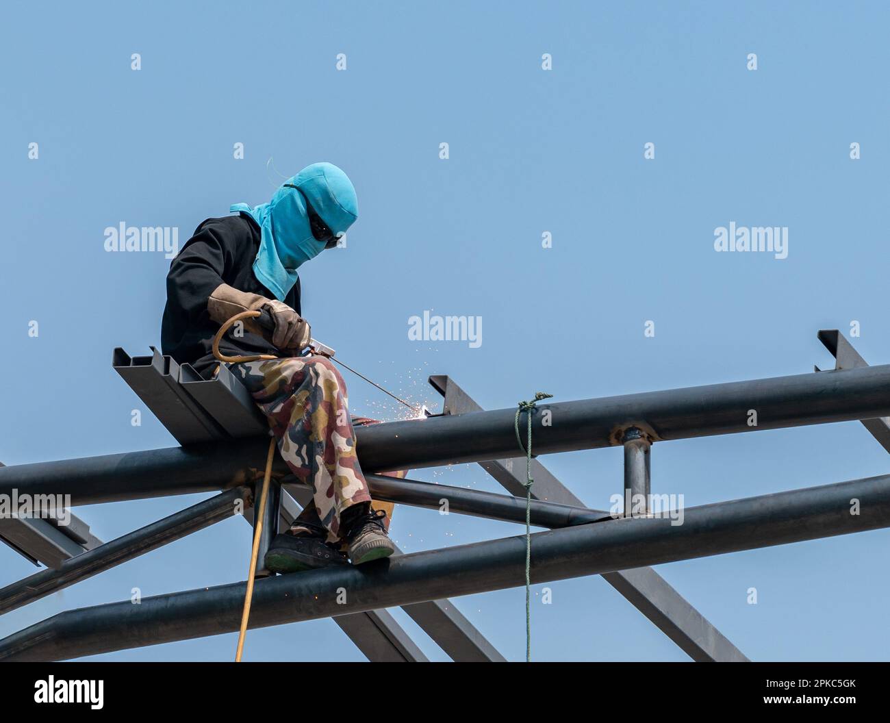A welder is welding steel on a steel roof truss. Working at height ...
