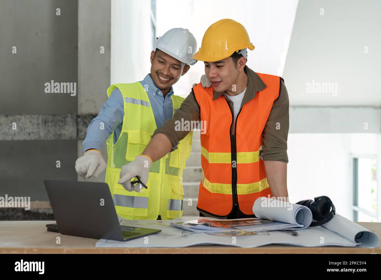 Young engineer with laptop computer explain to foreman about a floor ...