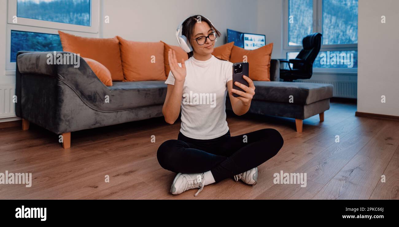 A woman doing home workout with headphones and smartphone for a video ...