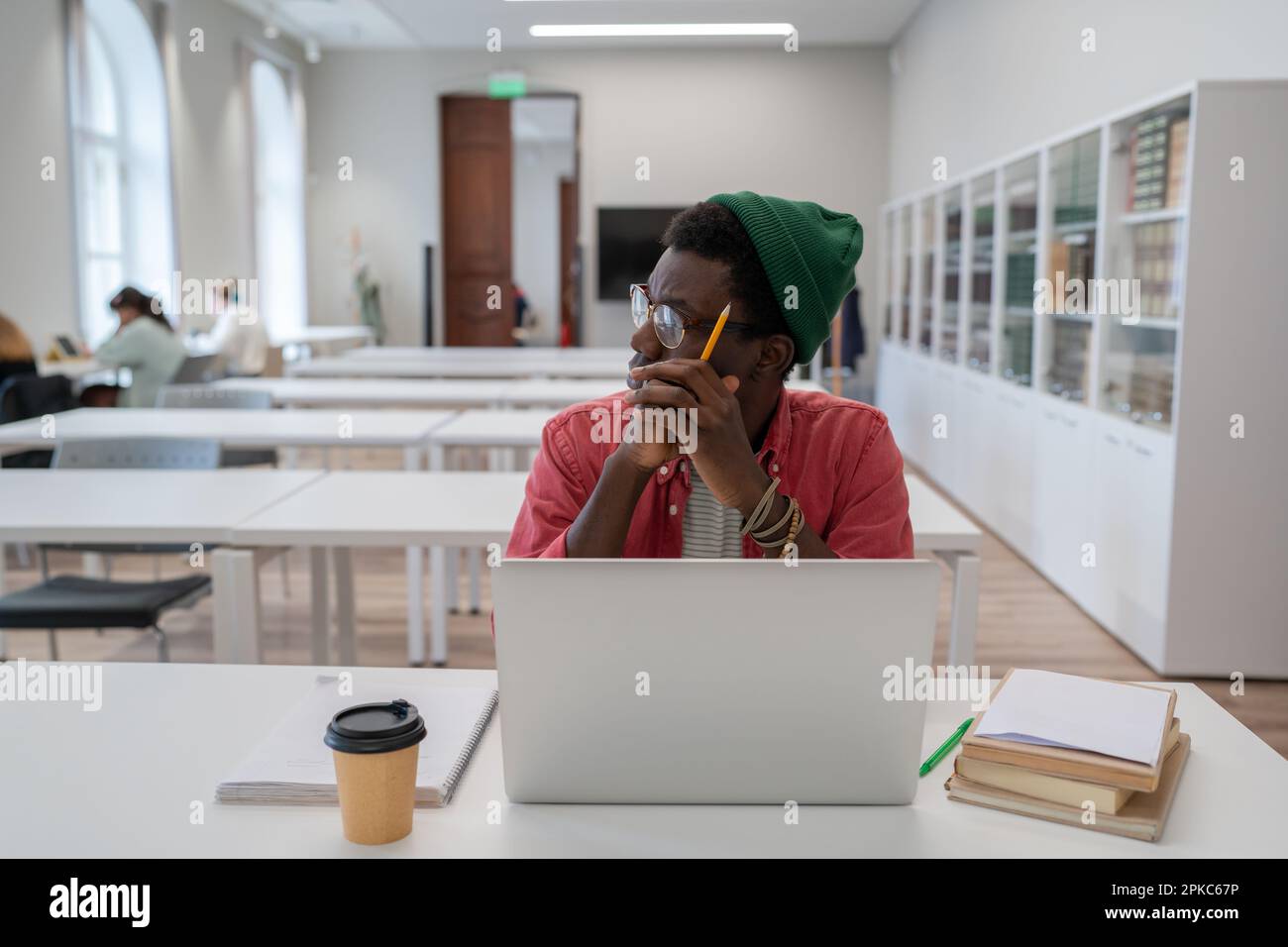 Thoughtful african american nerd man student studying in library using ...