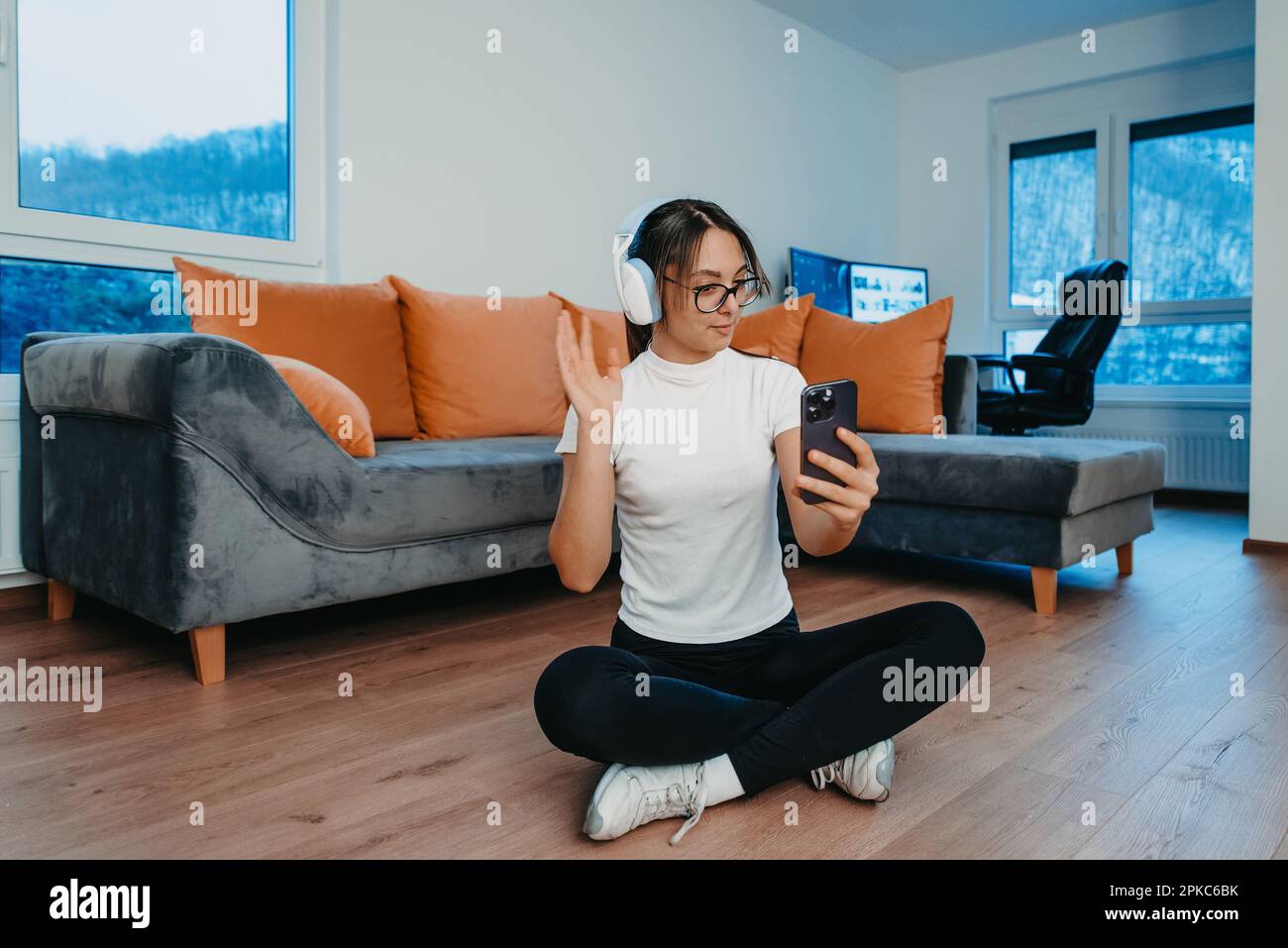 A woman doing home workout with headphones and smartphone for a video ...
