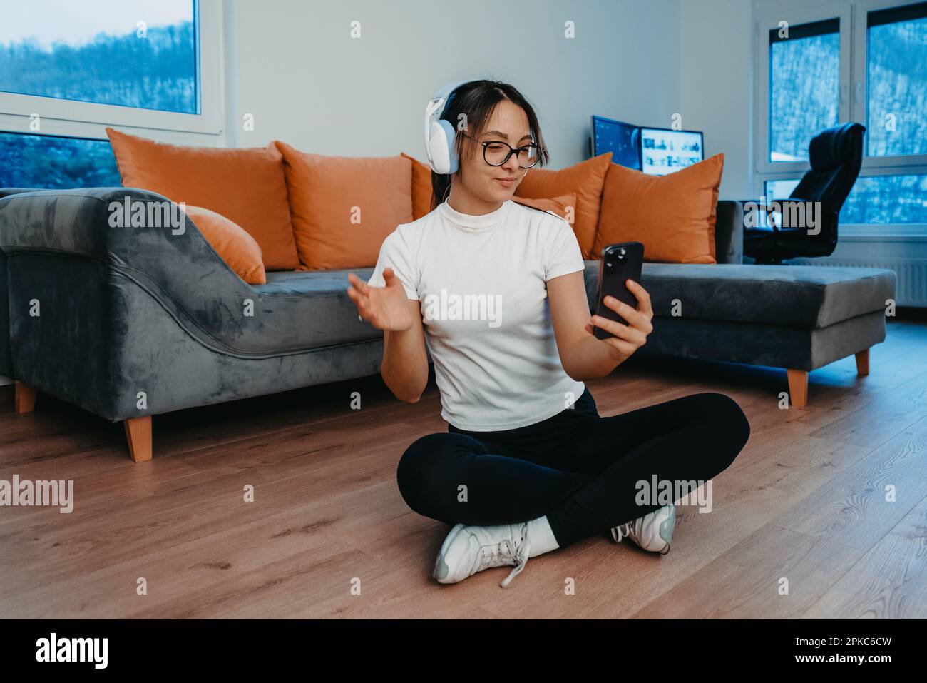 A woman doing home workout with headphones and smartphone for a video ...