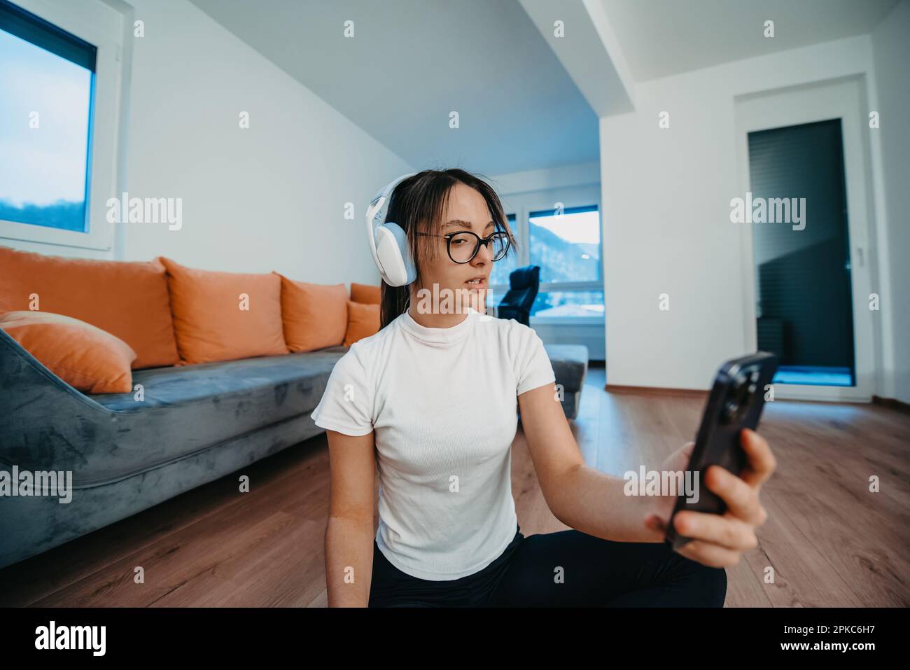 A woman doing home workout with headphones and smartphone for a video ...