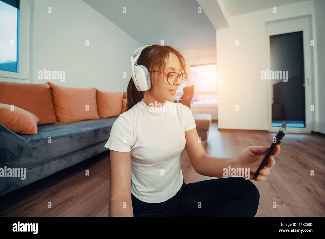 A woman doing home workout with headphones and smartphone for a video ...