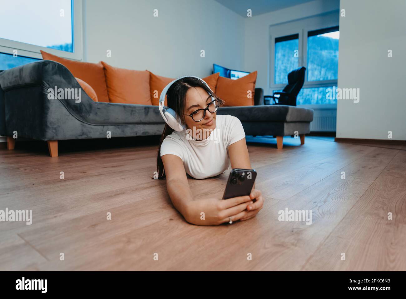 A woman doing home workout with headphones and smartphone for a video ...