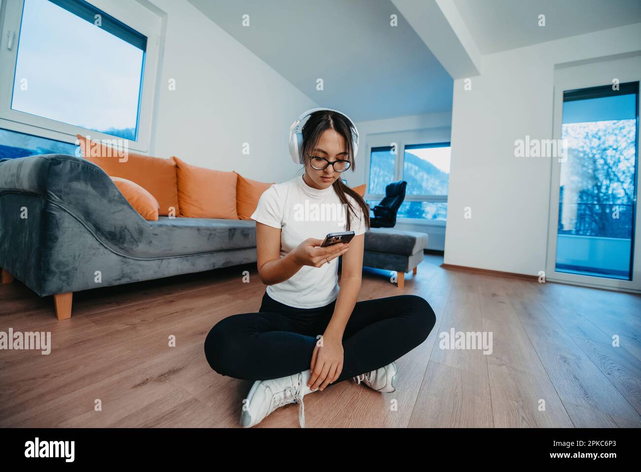 A woman doing home workout with headphones and smartphone for a video ...