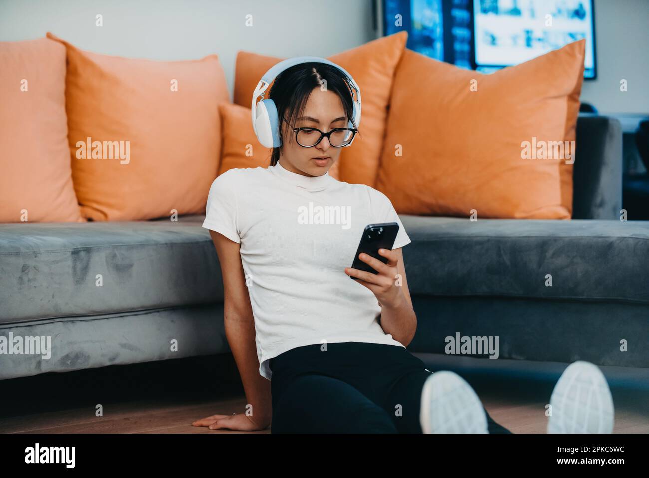A woman doing home workout with headphones and smartphone for a video ...