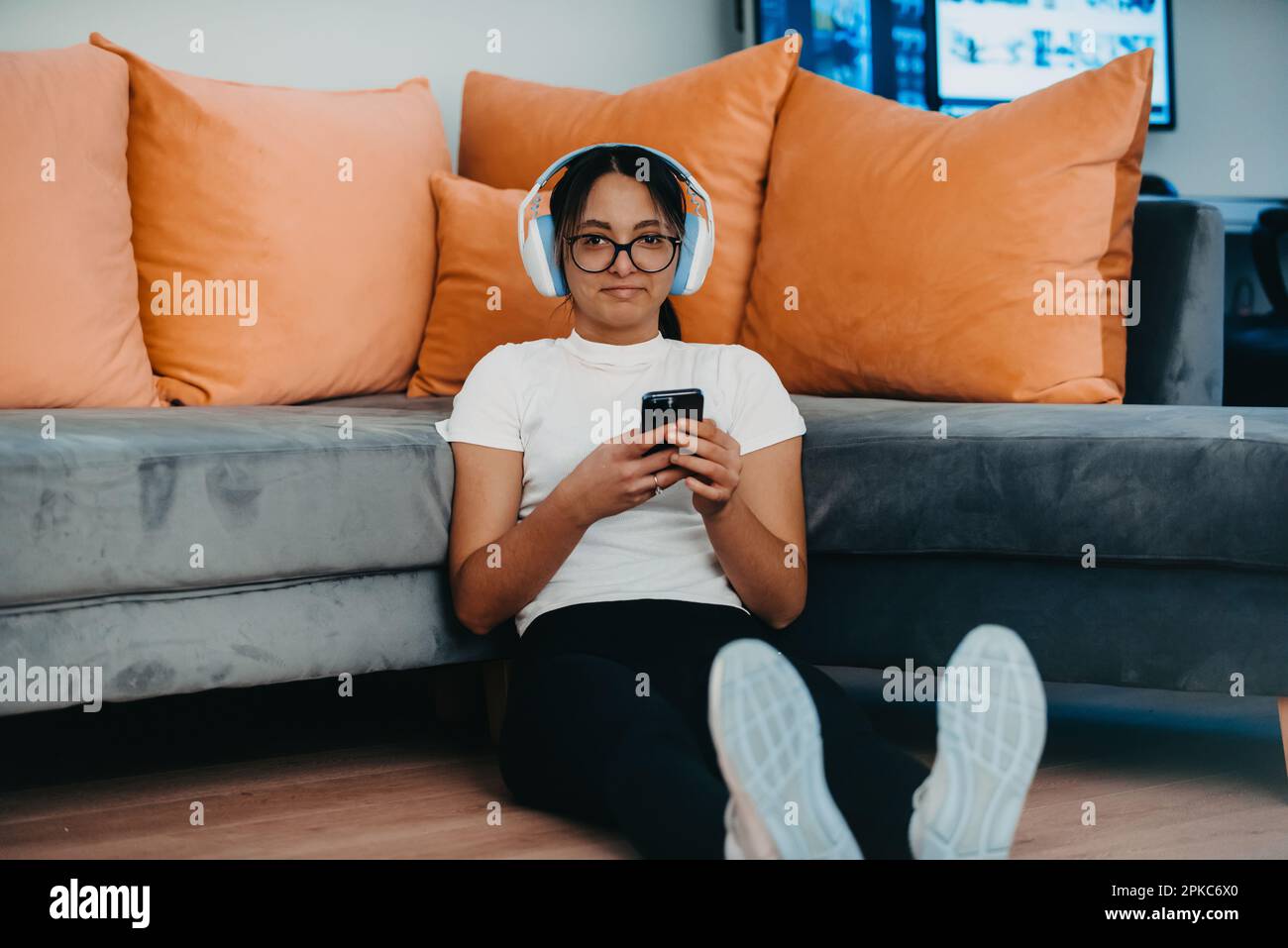 A woman doing home workout with headphones and smartphone for a video ...