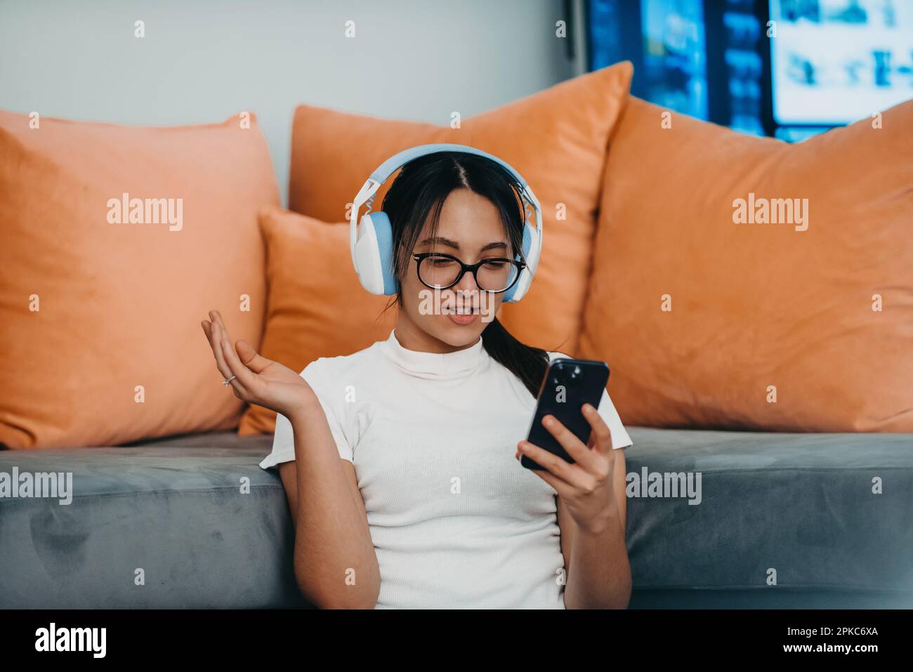 A woman doing home workout with headphones and smartphone for a video ...