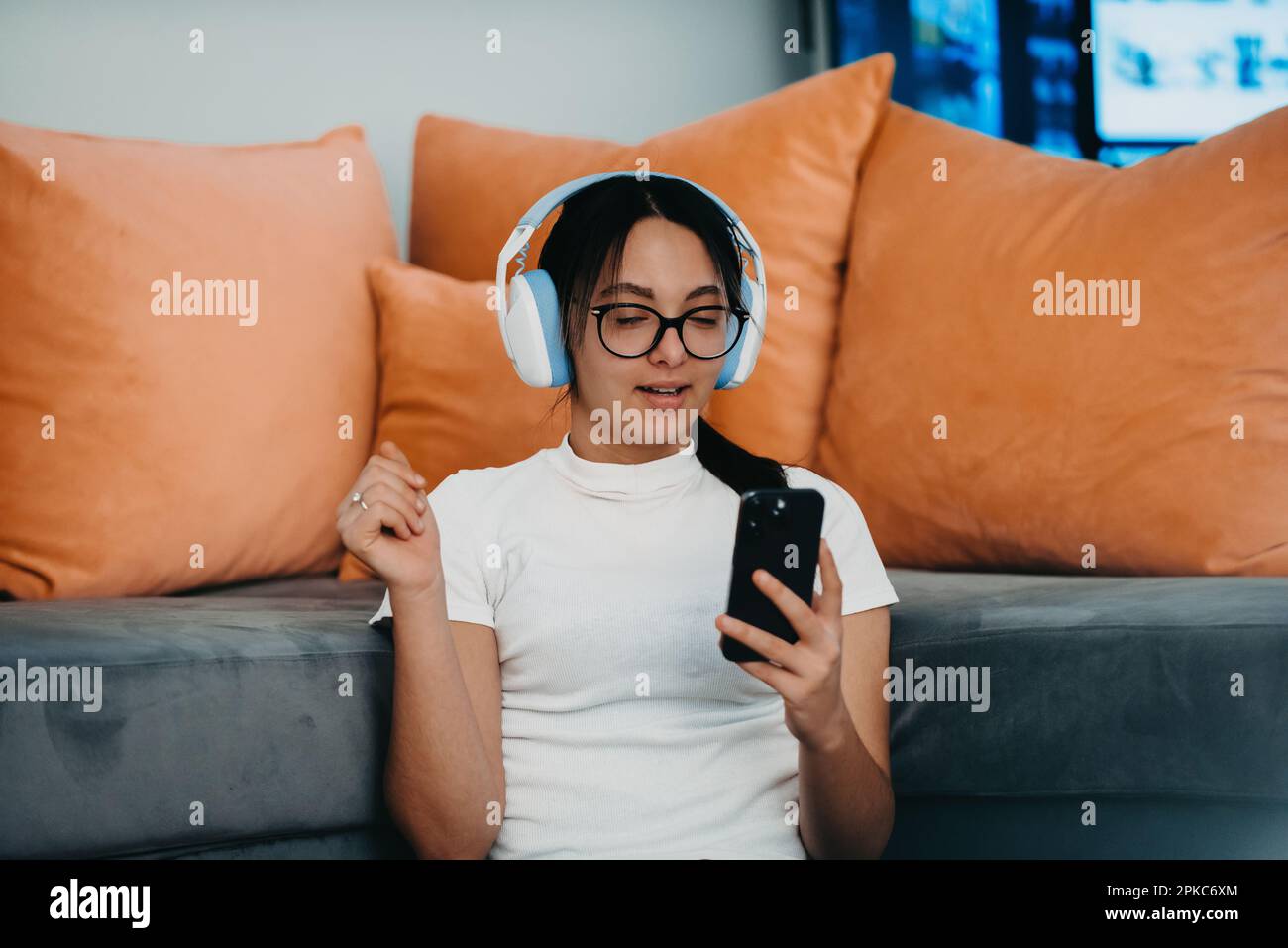 A woman doing home workout with headphones and smartphone for a video ...