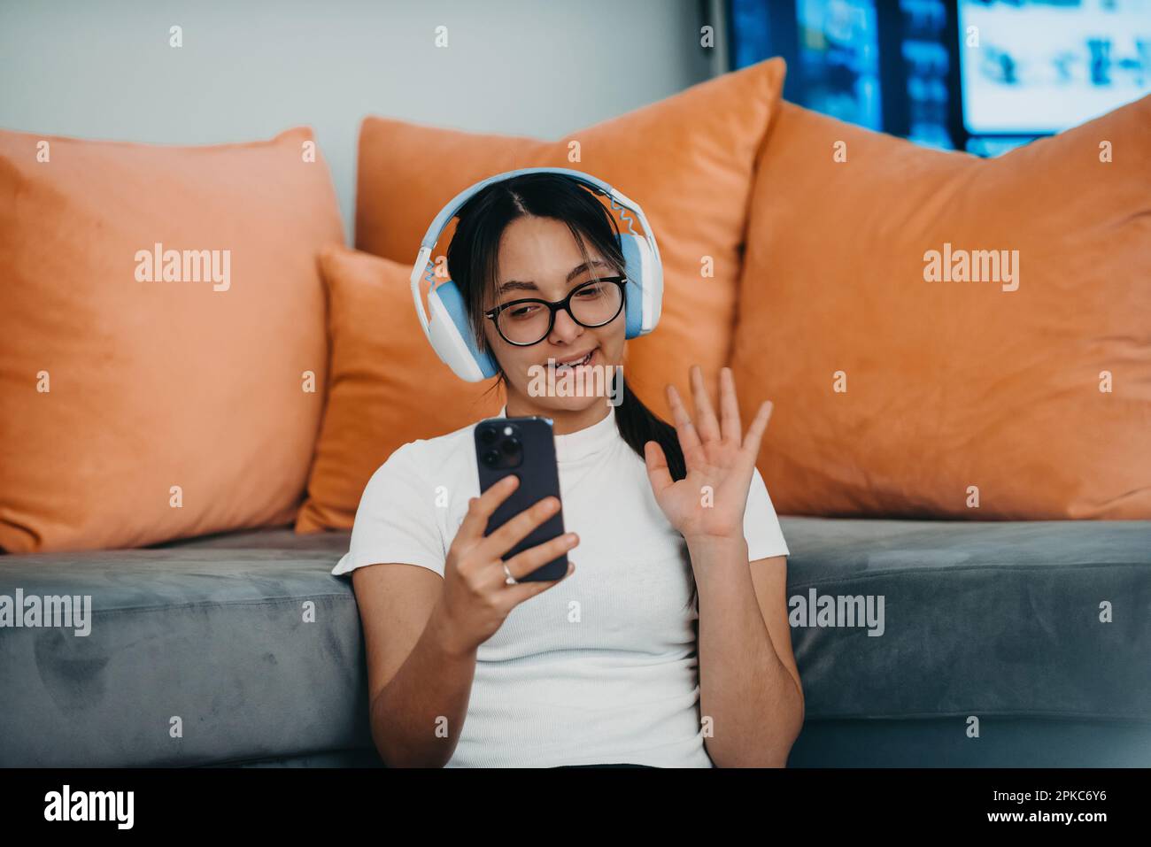 A woman doing home workout with headphones and smartphone for a video ...