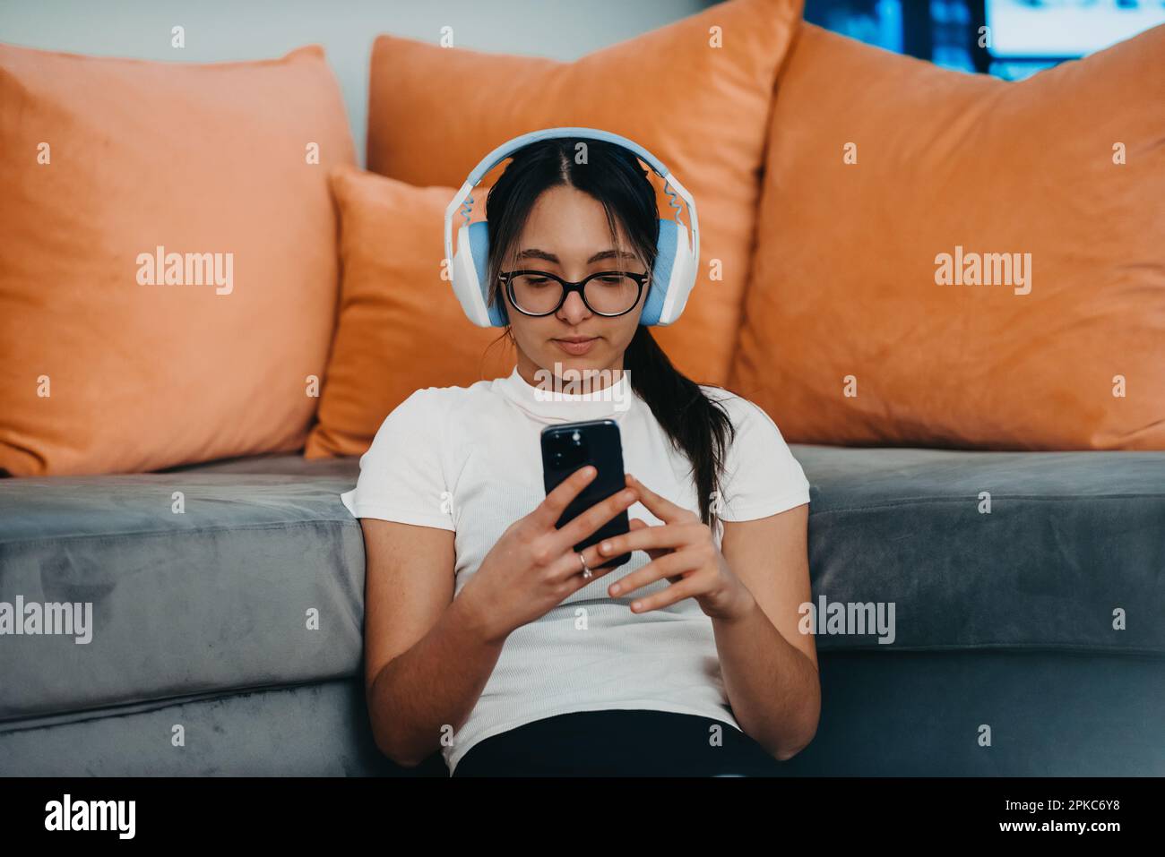 A woman doing home workout with headphones and smartphone for a video ...