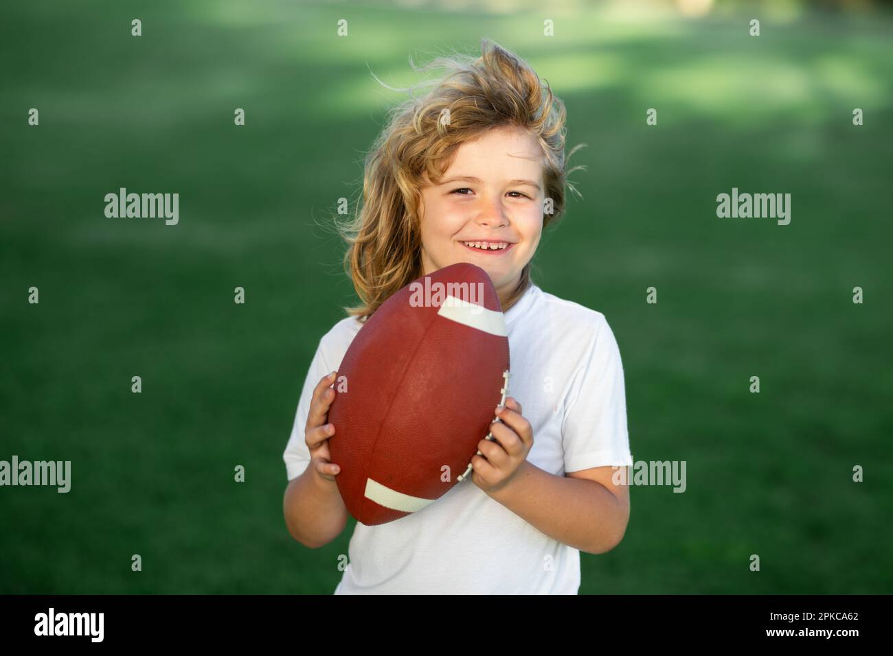 Sport kid. American boy playing a american football or rugby in park ...