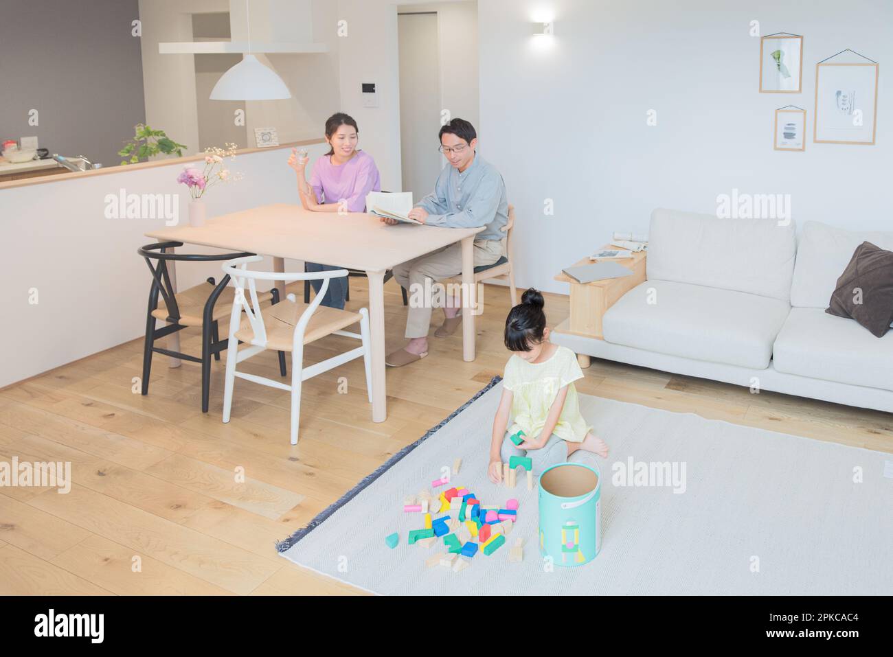 Daughter playing with toys in the living room with her parents watching ...