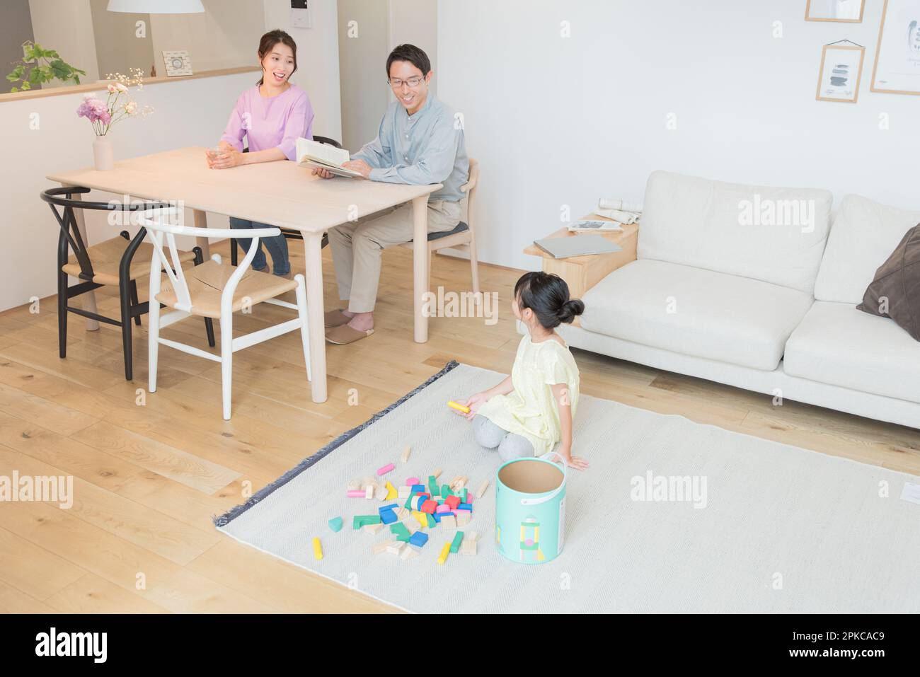 Daughter playing with toys in the living room with her parents watching ...