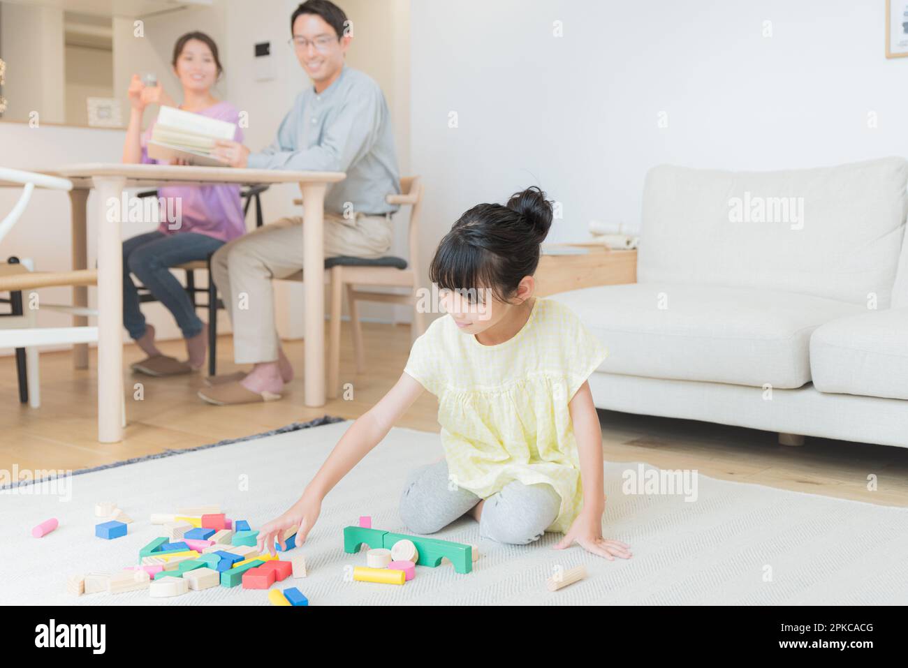 Daughter playing with toys in the living room with her parents watching ...