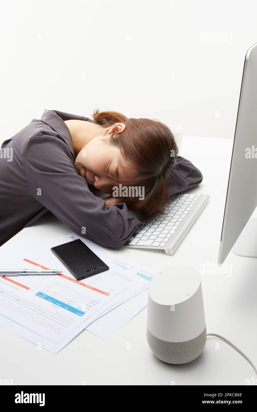 AI speaker next to a woman lying on her stomach at her work desk Stock ...
