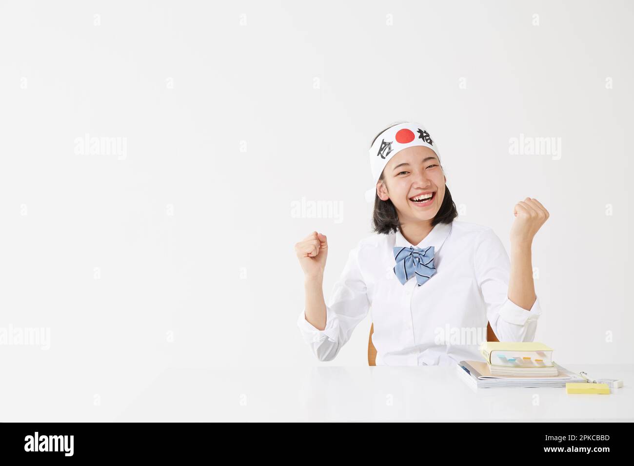 A high school girl wearing a "Hachimaki for Success" and posing with ...