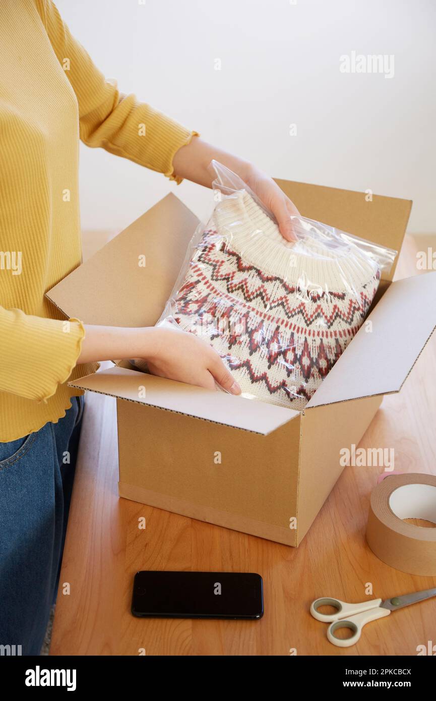 A woman packing folded sweaters into a box Stock Photo - Alamy