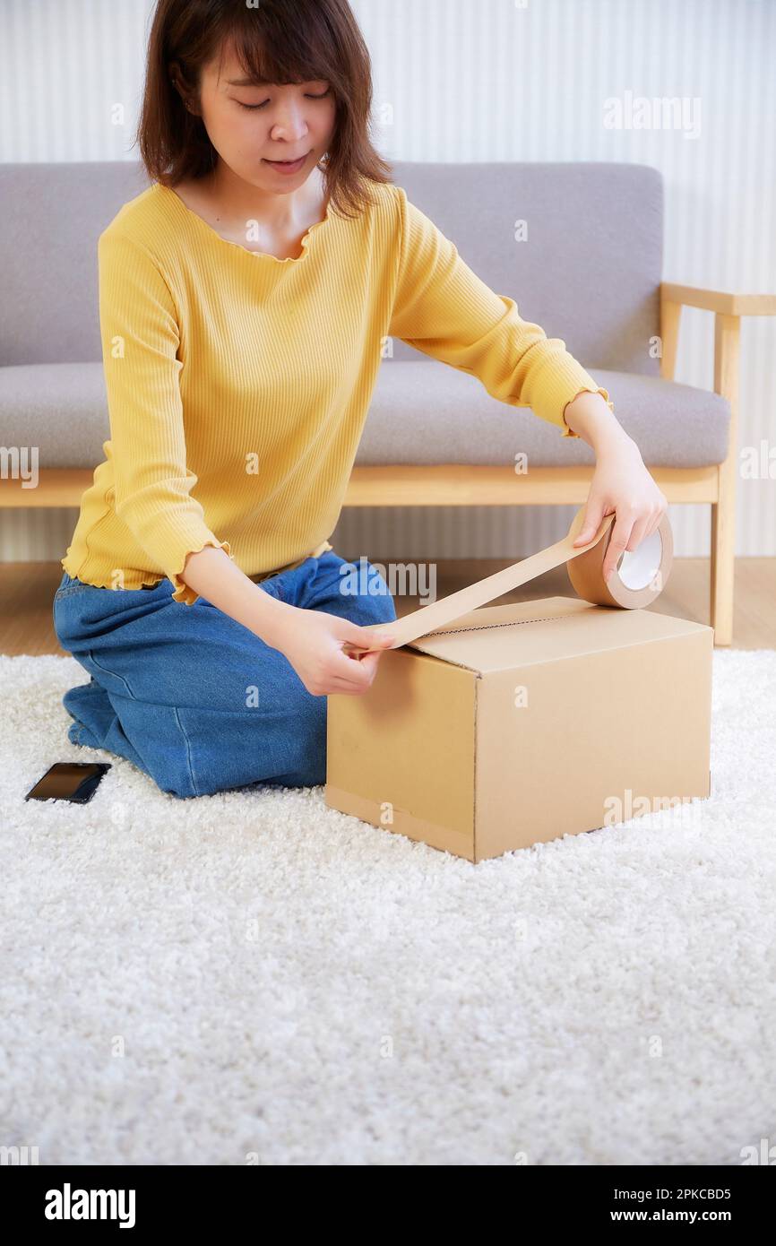 Woman closing the lid of a cardboard box with duct tape Stock Photo - Alamy