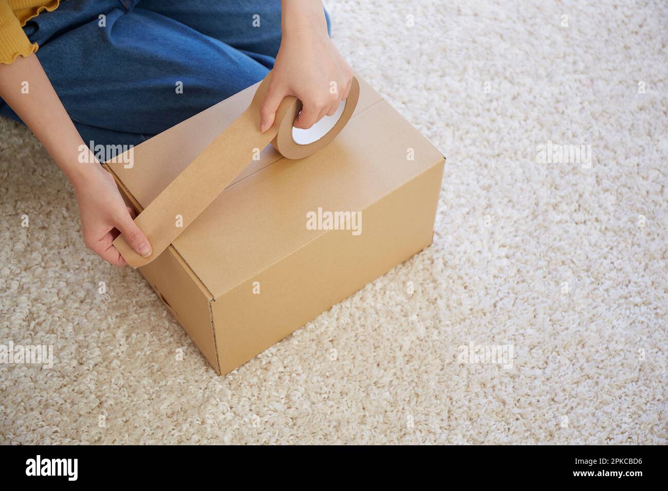 Woman closing the lid of a cardboard box with duct tape Stock Photo - Alamy