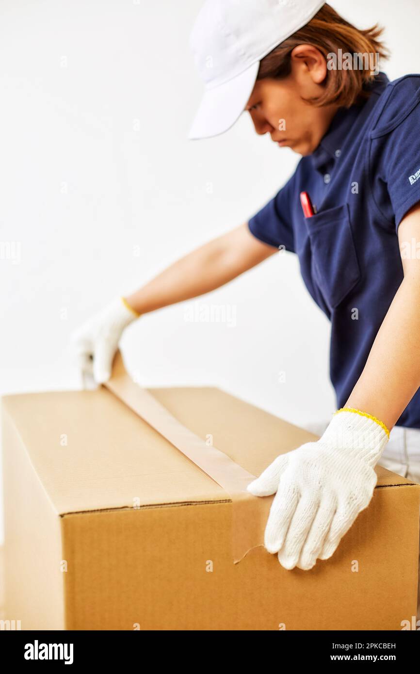 Female worker closing the lid of a cardboard box Stock Photo - Alamy