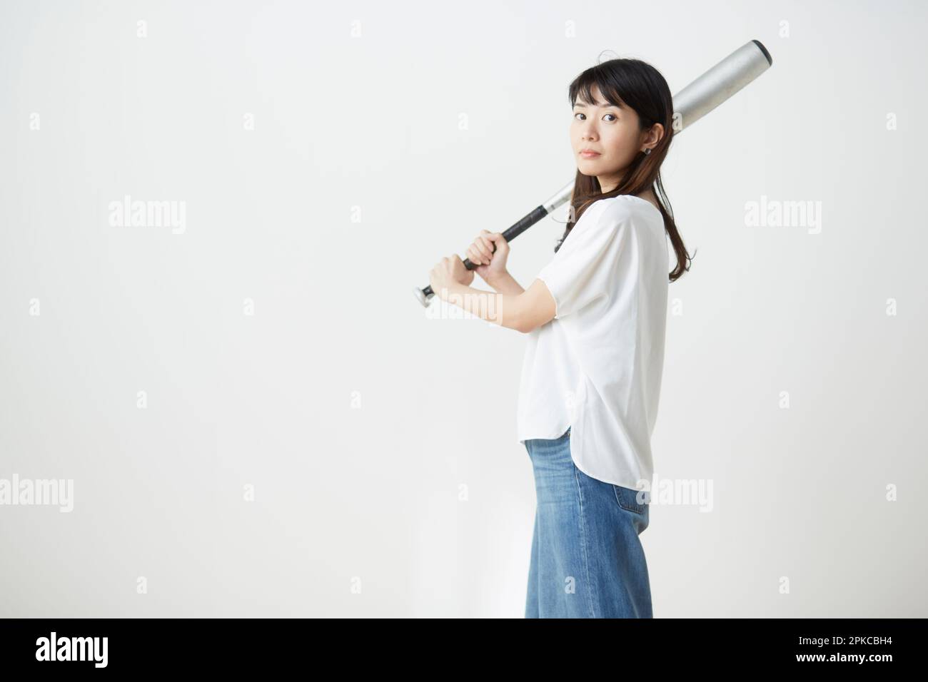Woman holding bat in front of white wall Stock Photo - Alamy