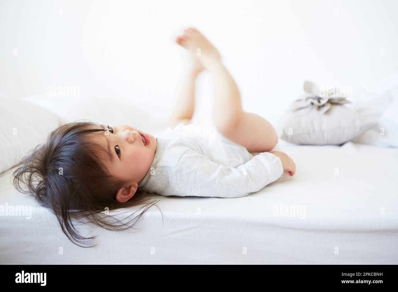Baby flailing on bed Stock Photo - Alamy