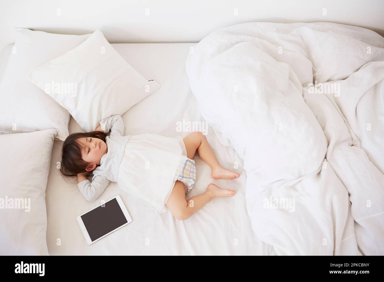 Baby sleeping alongside tablet on bed Stock Photo - Alamy