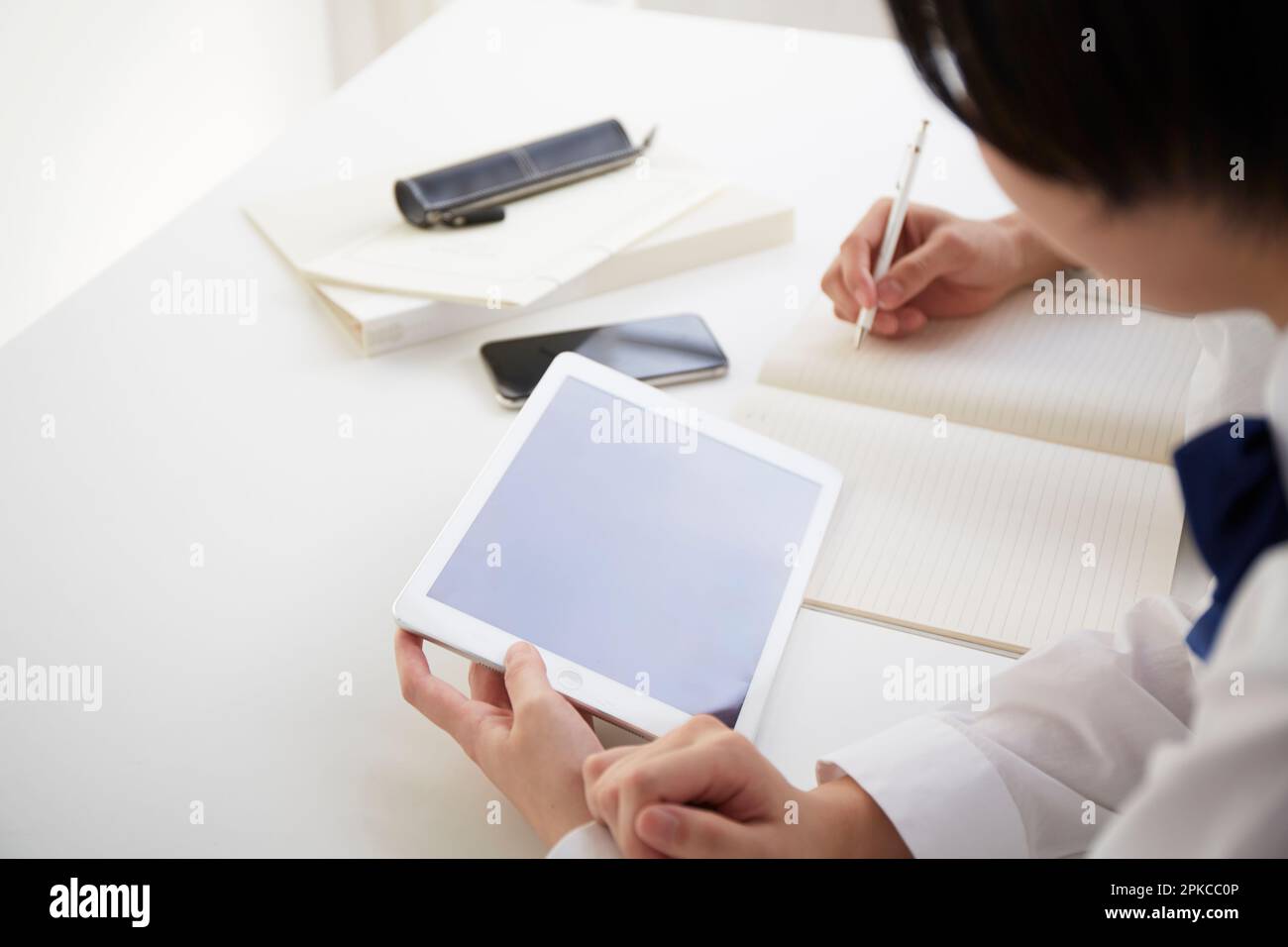 Male and female high school students studying using multiple devices on ...