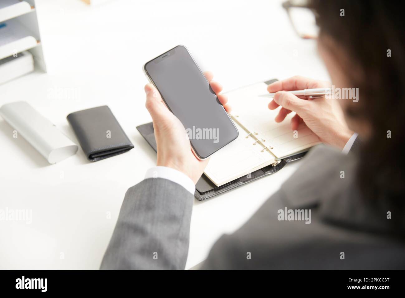 Office worker working while using a smartphone Stock Photo - Alamy