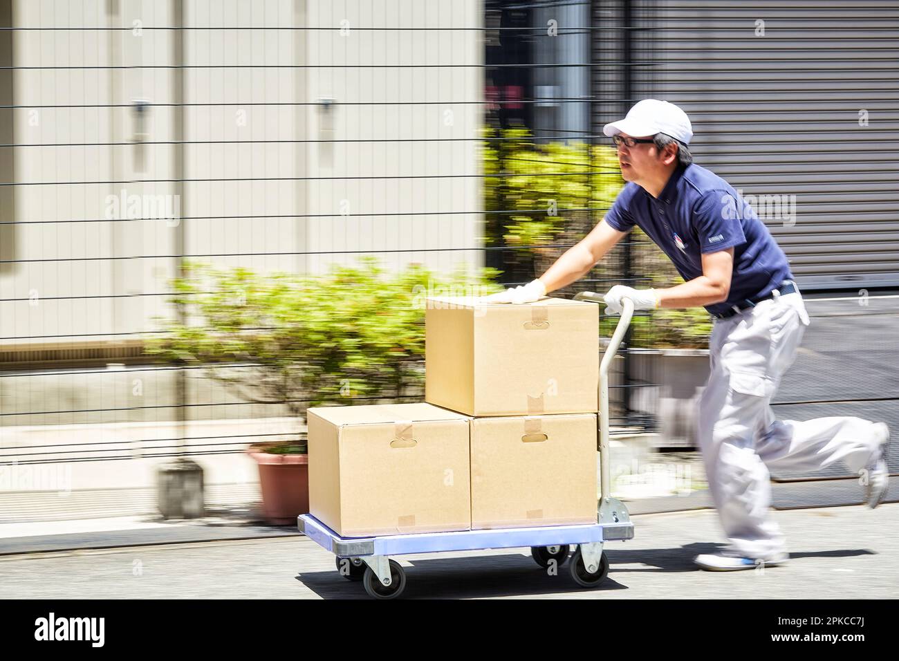 Man carrying cardboard boxes on a cart Stock Photo - Alamy