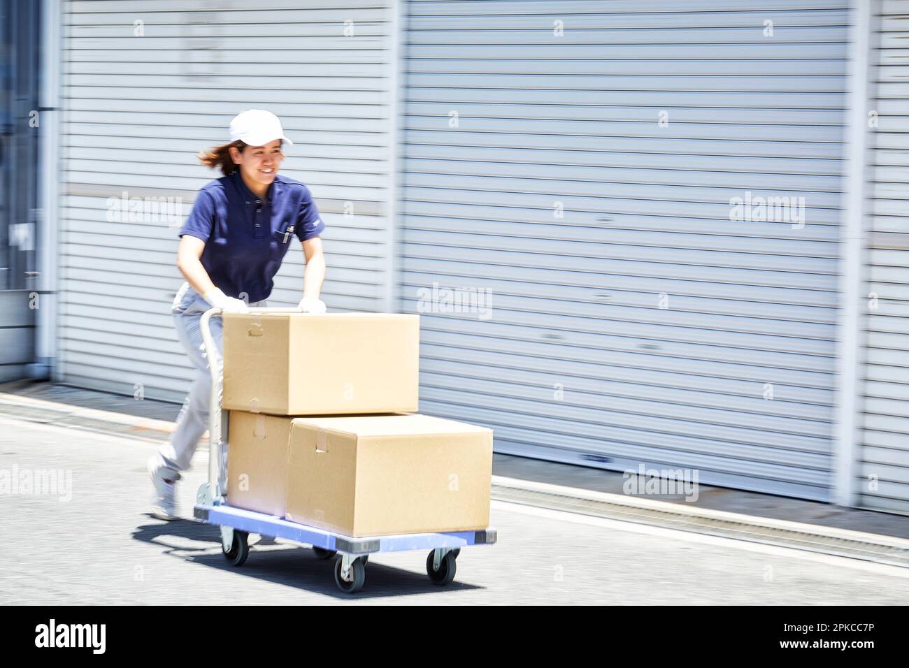Woman carrying cardboard boxes using a cart Stock Photo - Alamy